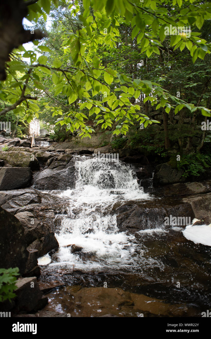 Waterfall flowing over rocks in a forest setting Stock Photo - Alamy