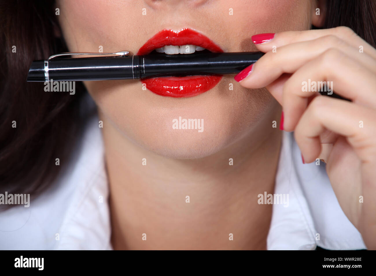Woman with pen in mouth Stock Photo - Alamy