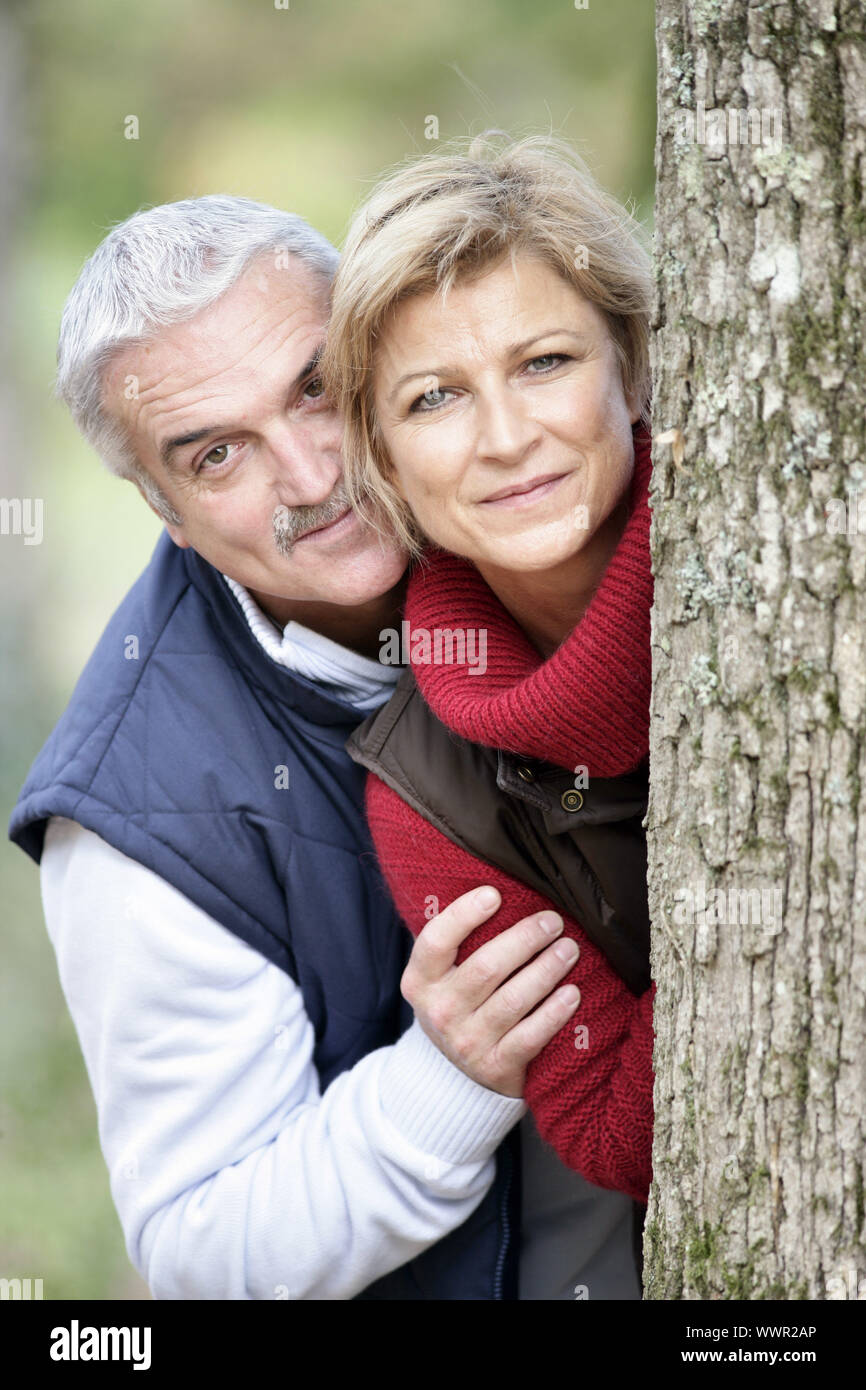 Older couple peeking around a tree Stock Photo - Alamy