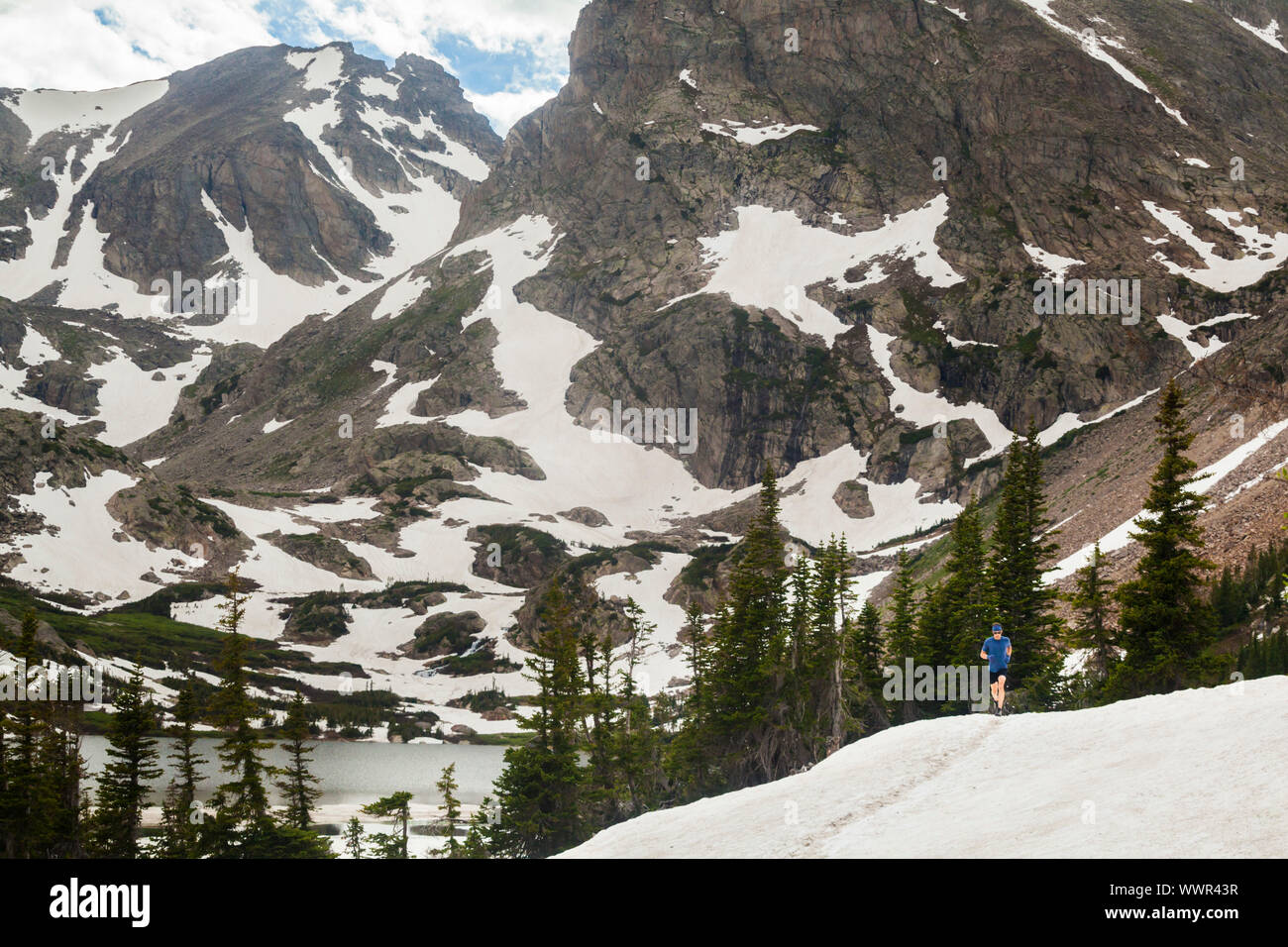 A man runs over snow on the Isabelle Glacier Trail above Lake Isabelle ...