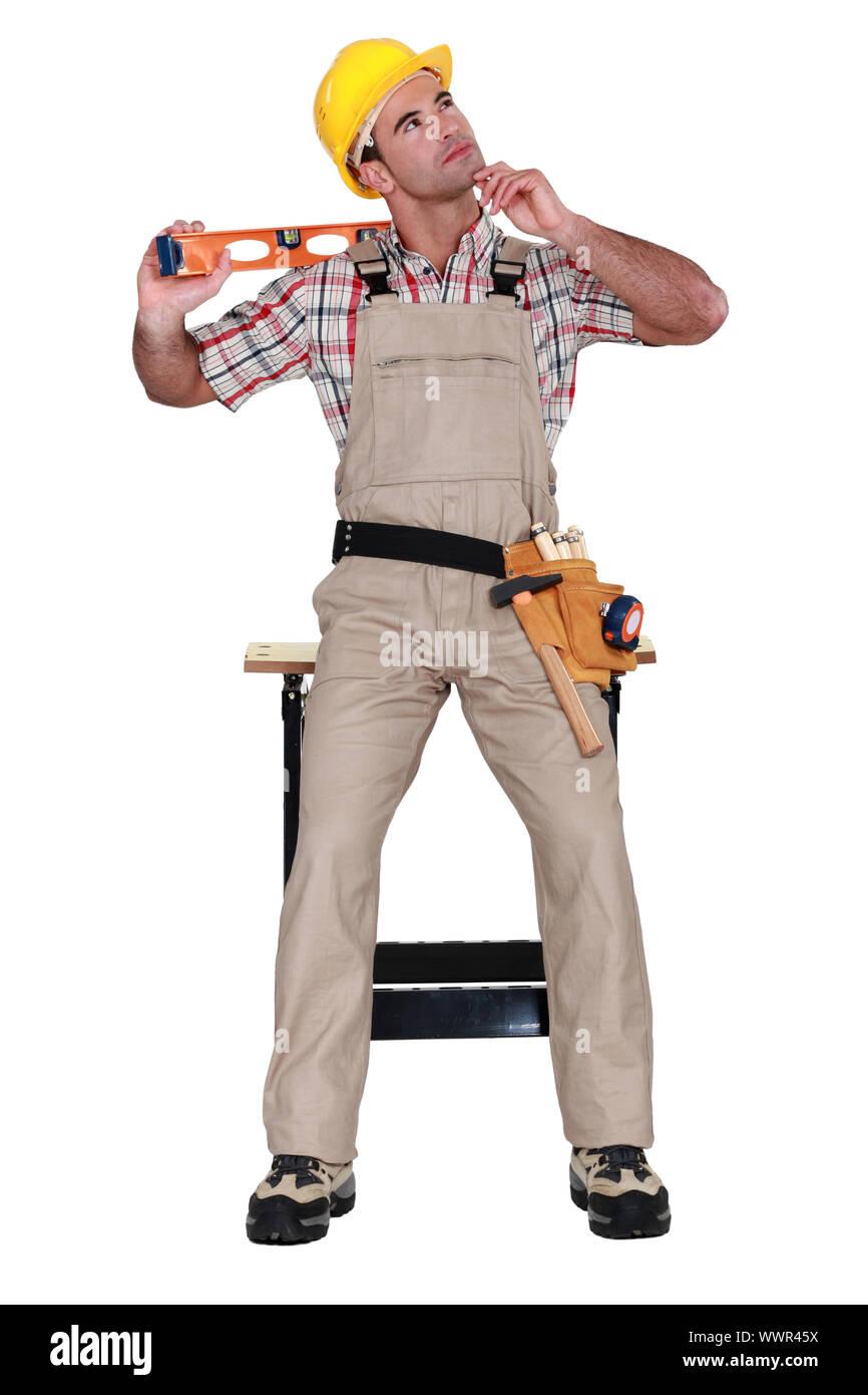 carpenter holding a level and thinking Stock Photo - Alamy