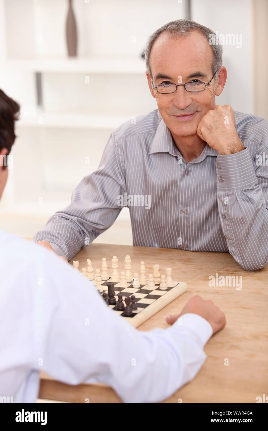 grandpa playing chess game with grandson Stock Photo - Alamy