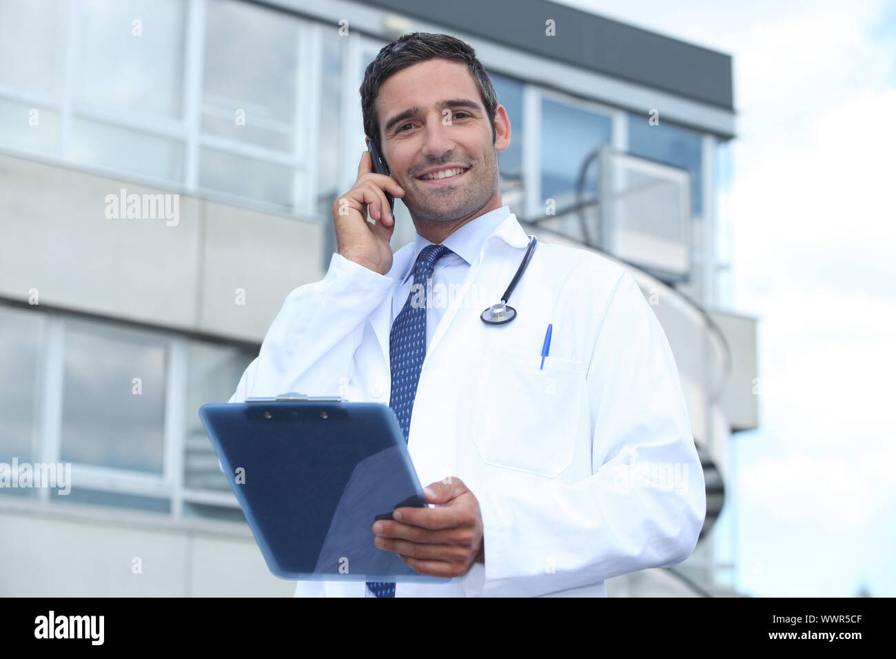 Male doctor outside hospital making phone call Stock Photo - Alamy