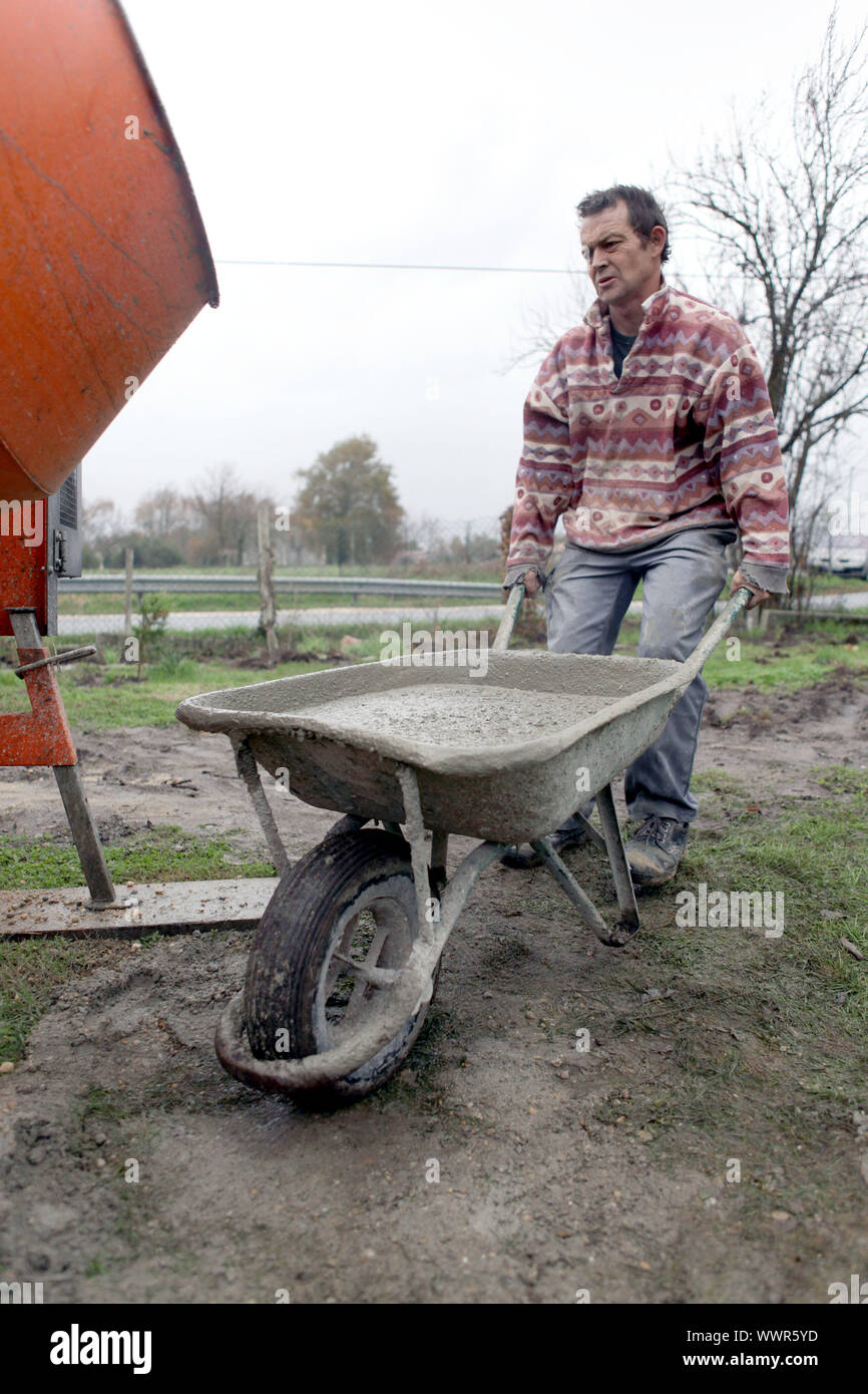 Man transporting cement in wheelbarrow Stock Photo - Alamy