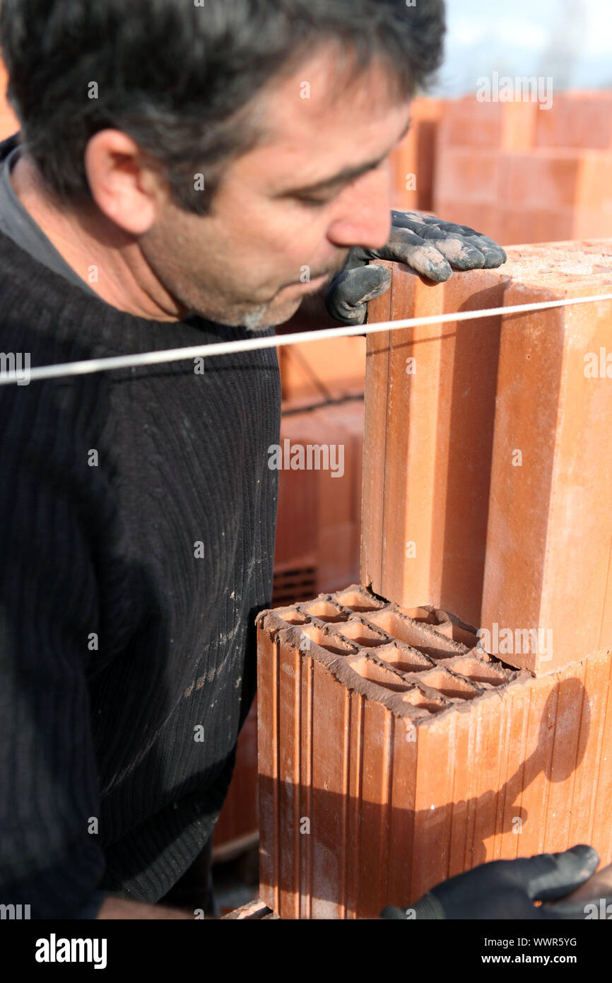 Bricklayer building wall Stock Photo - Alamy