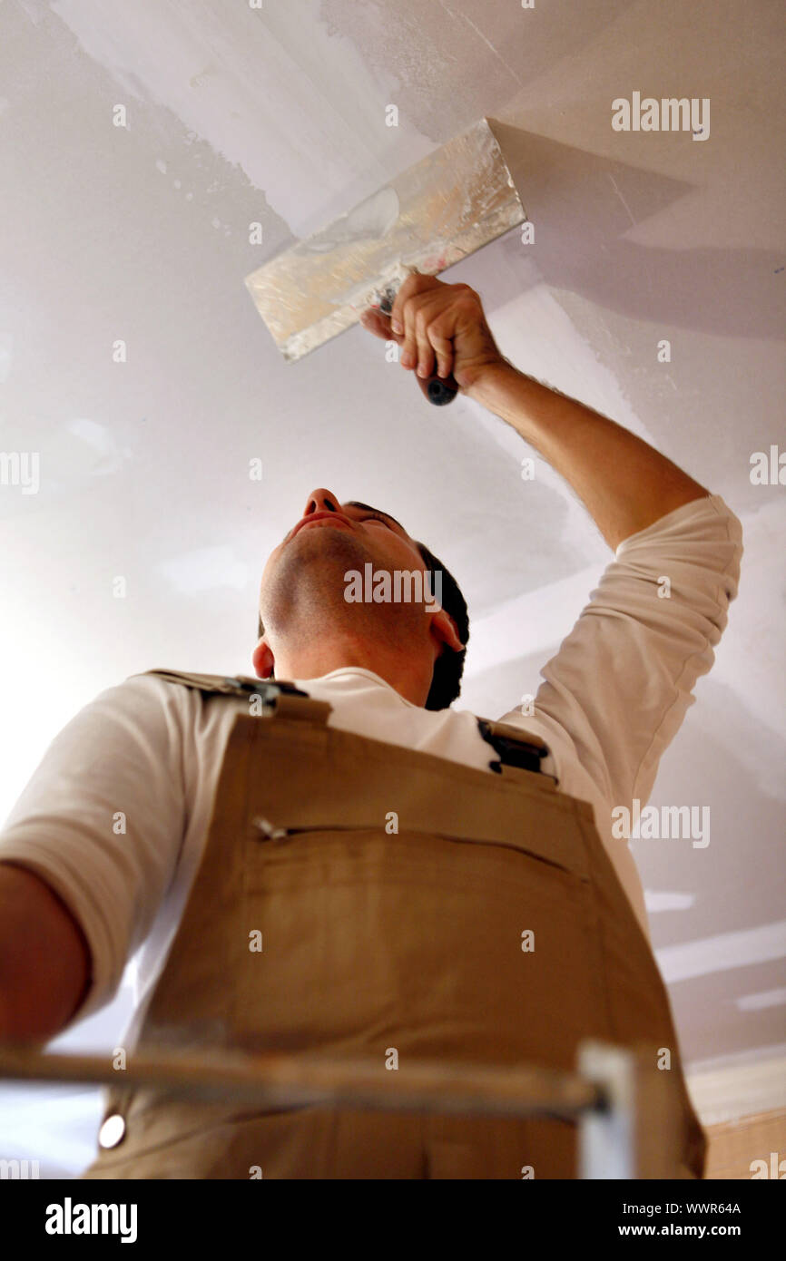 Man putting up a plasterboard ceiling Stock Photo - Alamy