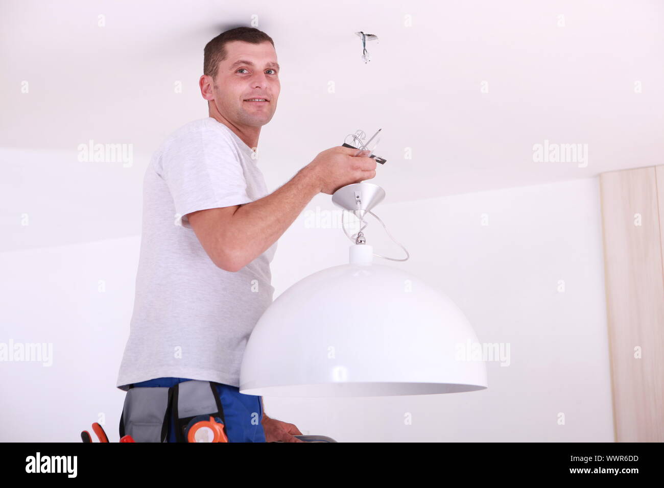 Man installing a ceiling light Stock Photo - Alamy