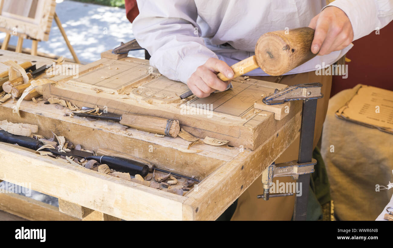 Carpenter, craftsman carving wood in a medieval fair, carpentry tools ...