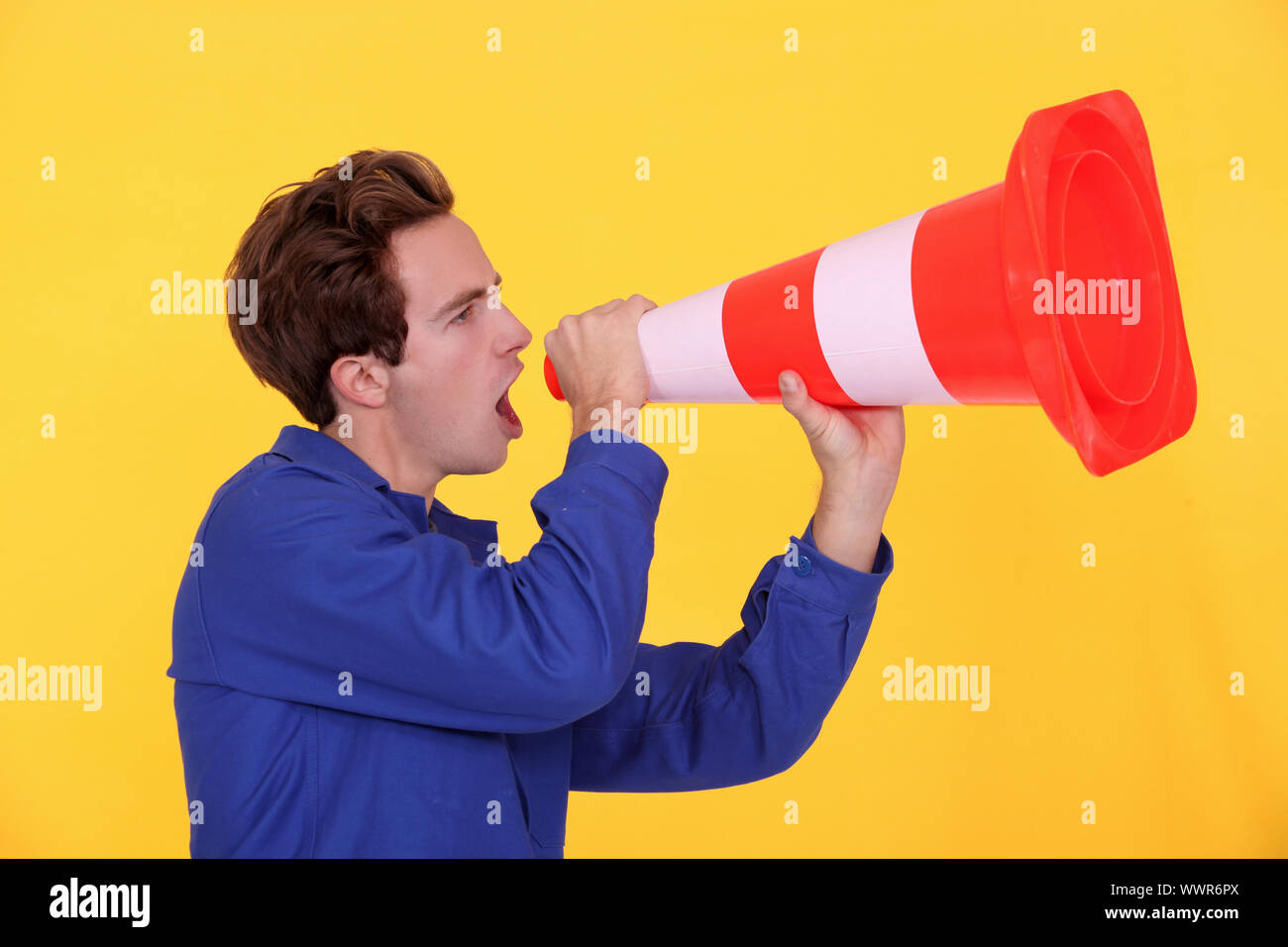 young blue collar shouting in construction cone Stock Photo - Alamy