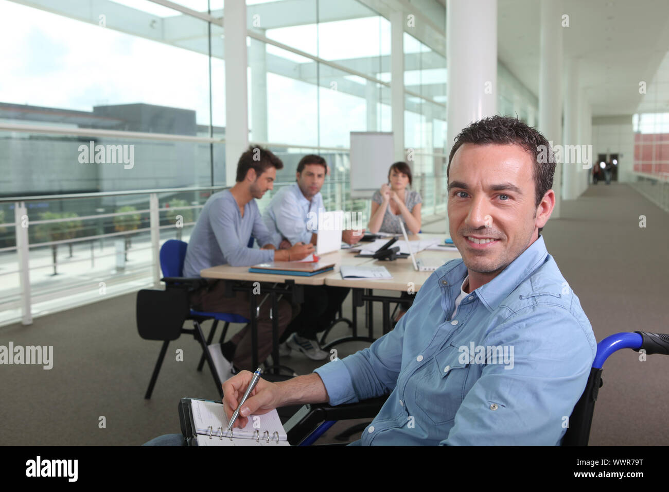 Man in a wheelchair working in an office Stock Photo - Alamy