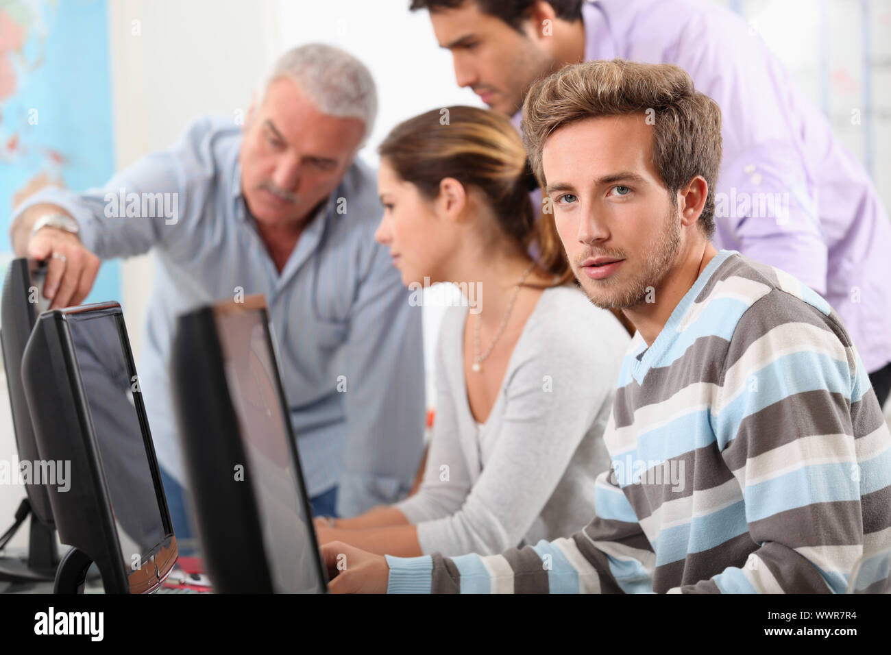 Teacher and students gathered around computer screen Stock Photo - Alamy