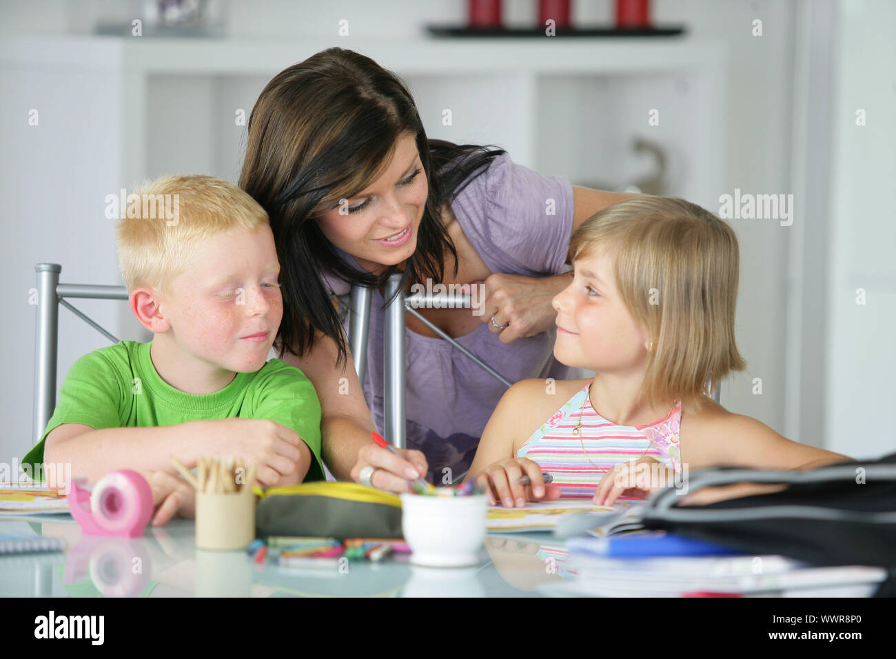 Mother watching brother and sister doing their homework Stock Photo - Alamy