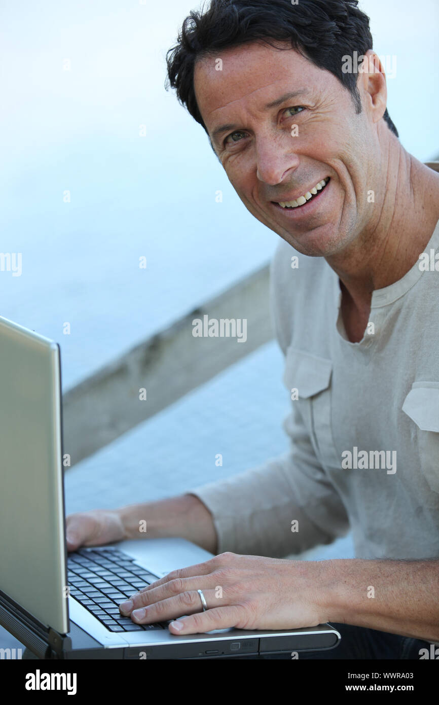 Man sat outdoors with laptop computer Stock Photo - Alamy