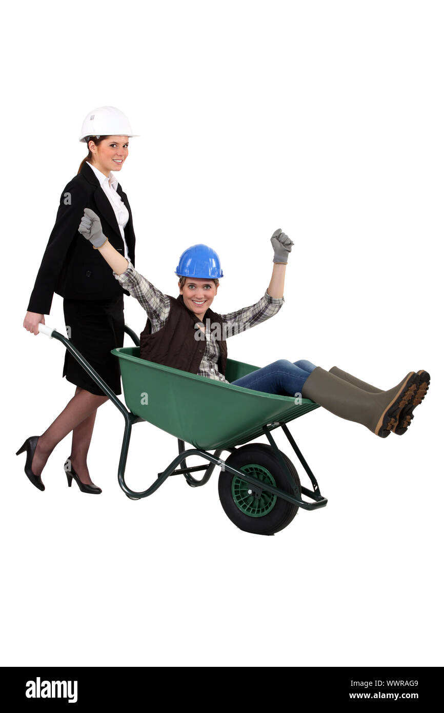 businesswoman carrying a craftswoman in a wheelbarrow Stock Photo - Alamy