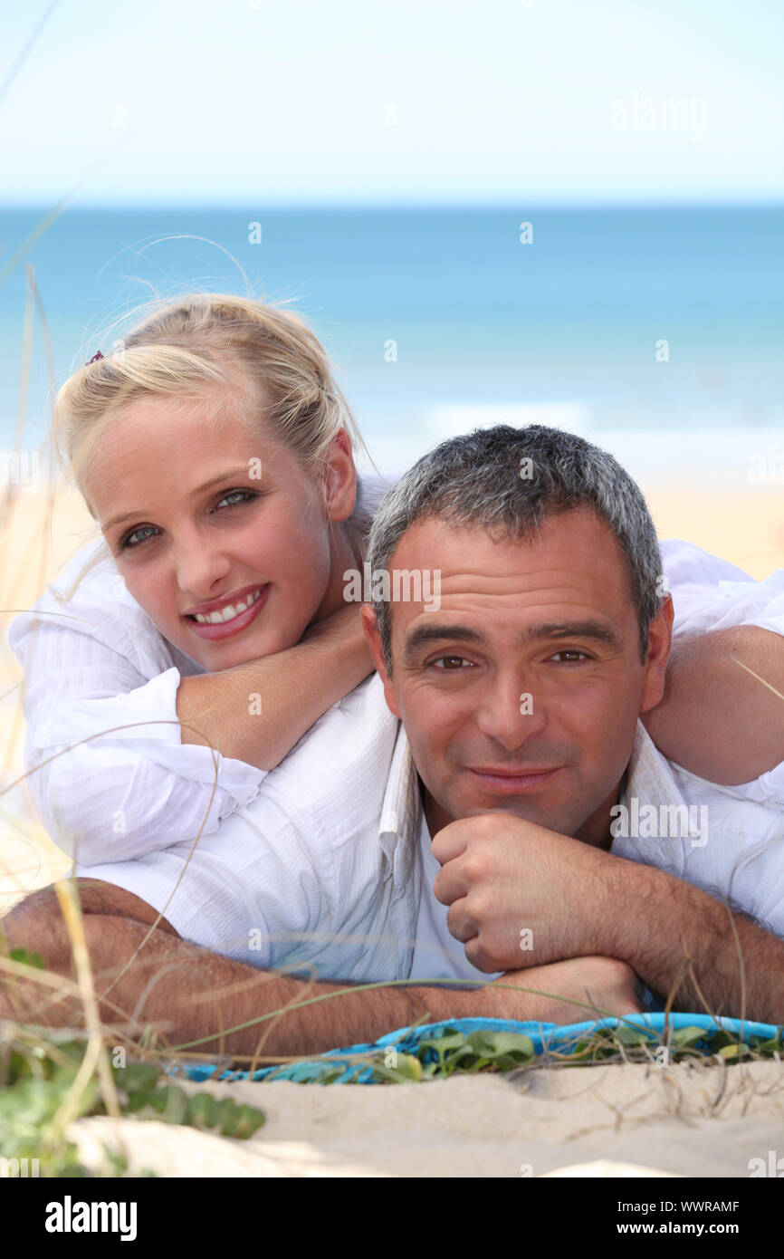 Couple lying on the sand Stock Photo - Alamy