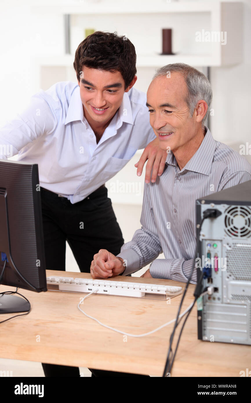 Younger and older men looking at a computer Stock Photo - Alamy