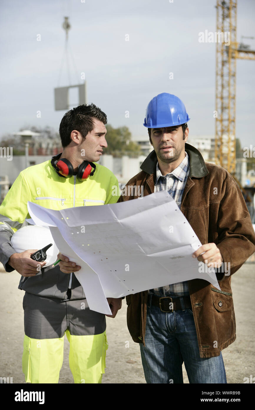 Construction workers looking at site plans Stock Photo - Alamy