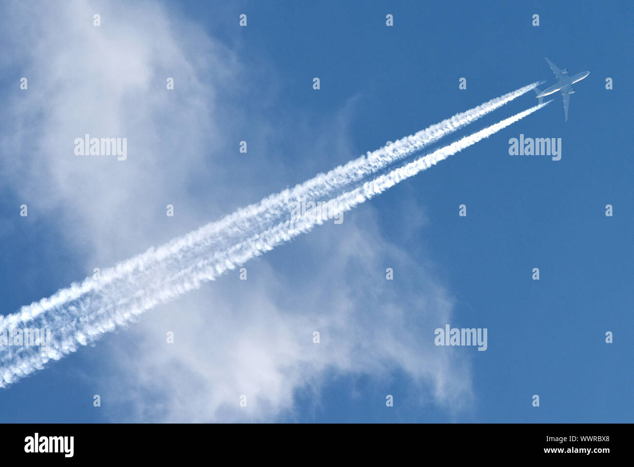 Airplane In Blue Clear Sky With Plane Trails Stock Photo - Alamy
