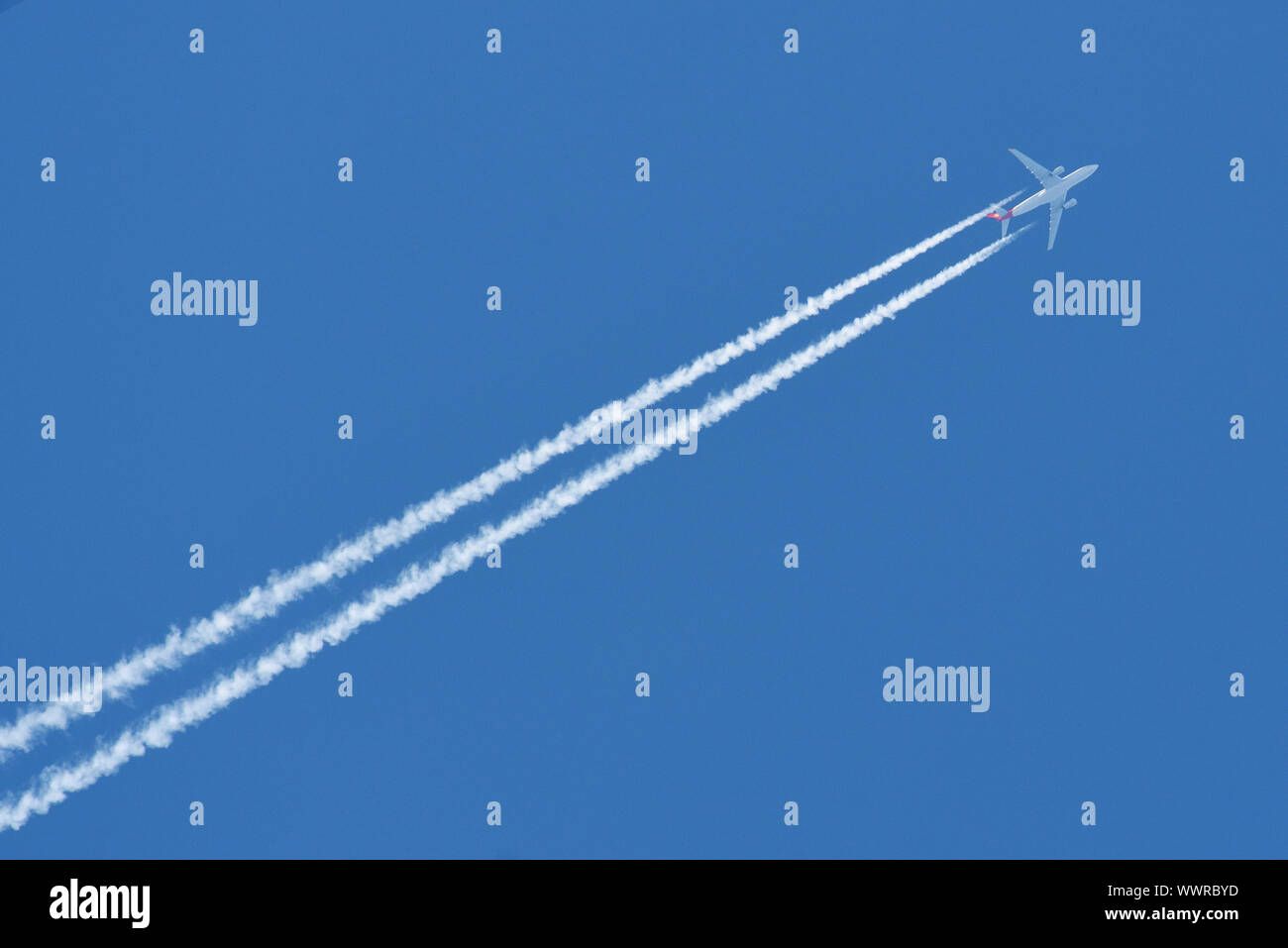 Airplane In Blue Clear Sky With Plane Trails Stock Photo - Alamy