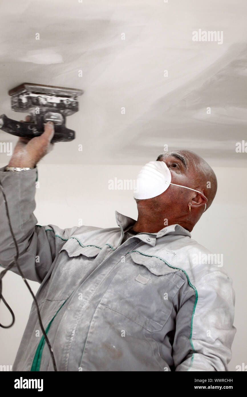 Man wearing mask whilst sanding ceiling Stock Photo - Alamy