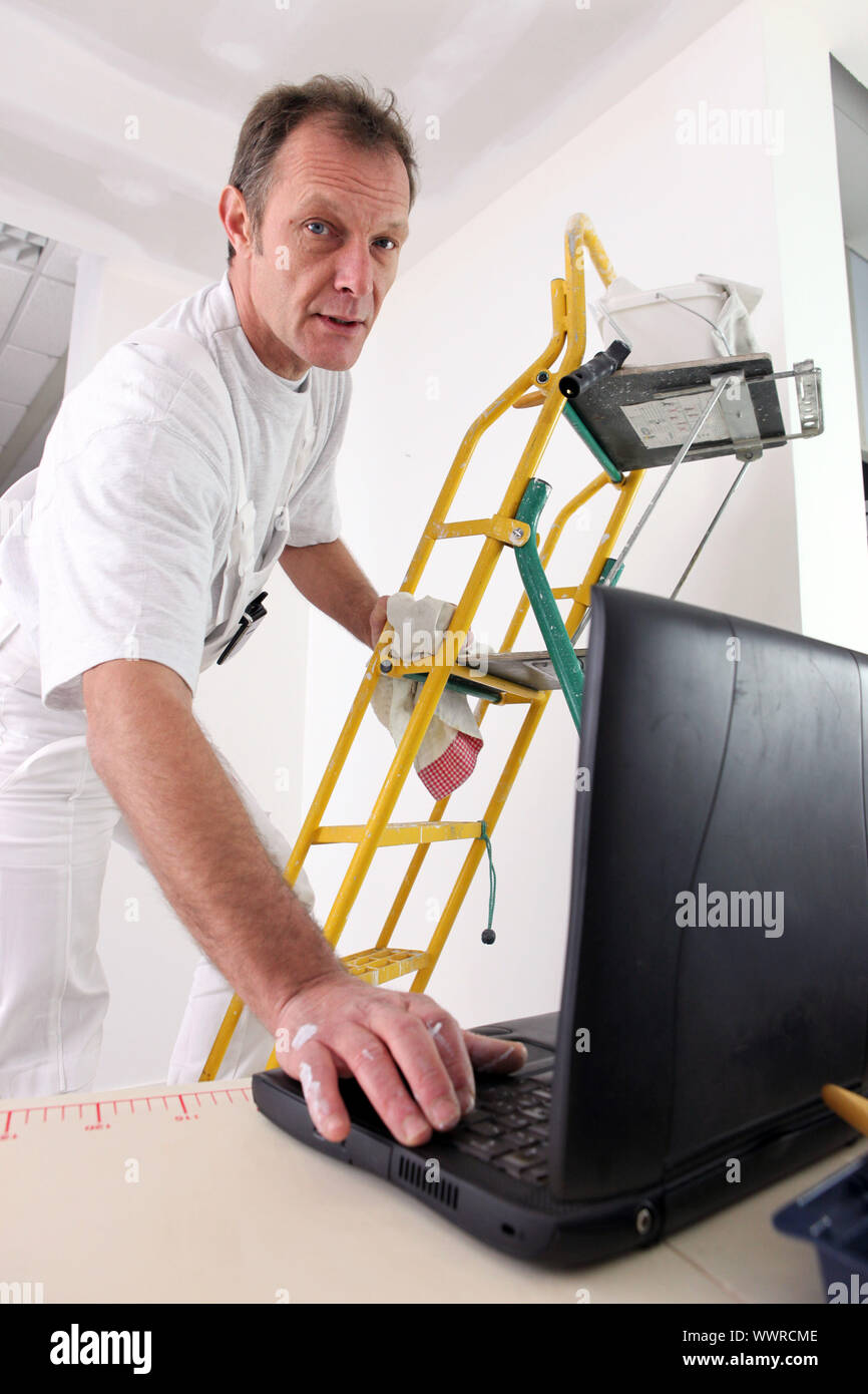 Painter checking instructions on the Internet Stock Photo - Alamy