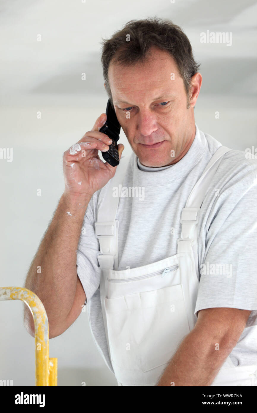Painter stopping work to take call Stock Photo - Alamy