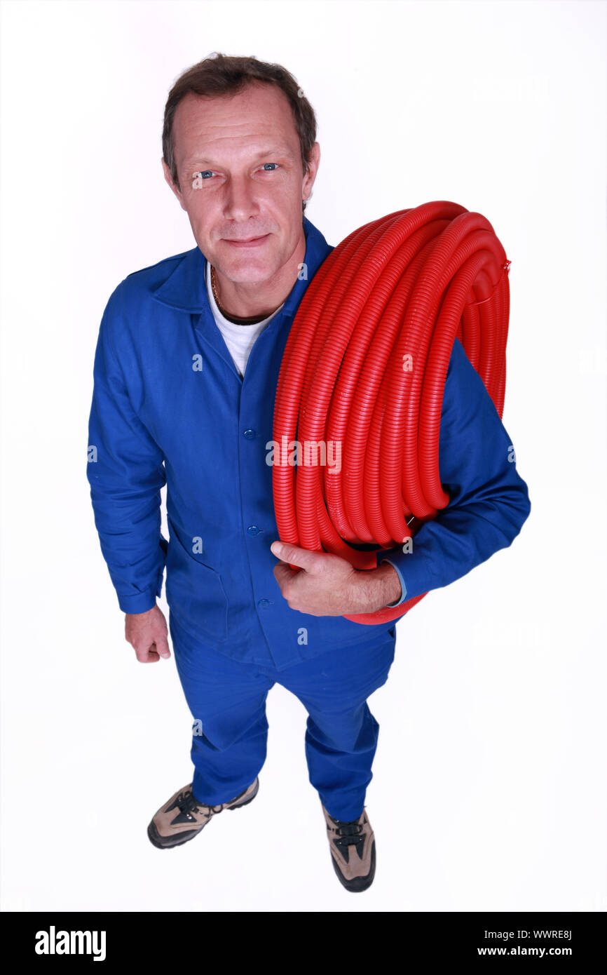 Plumber with large reel of red flexible pipe Stock Photo - Alamy