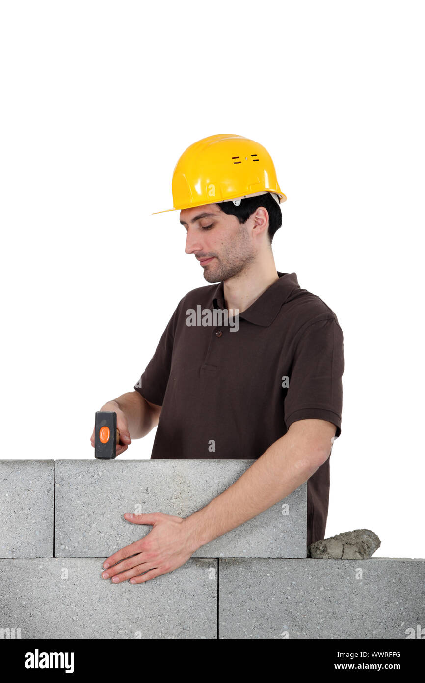 Mason using hammer to adjust brick wall Stock Photo - Alamy