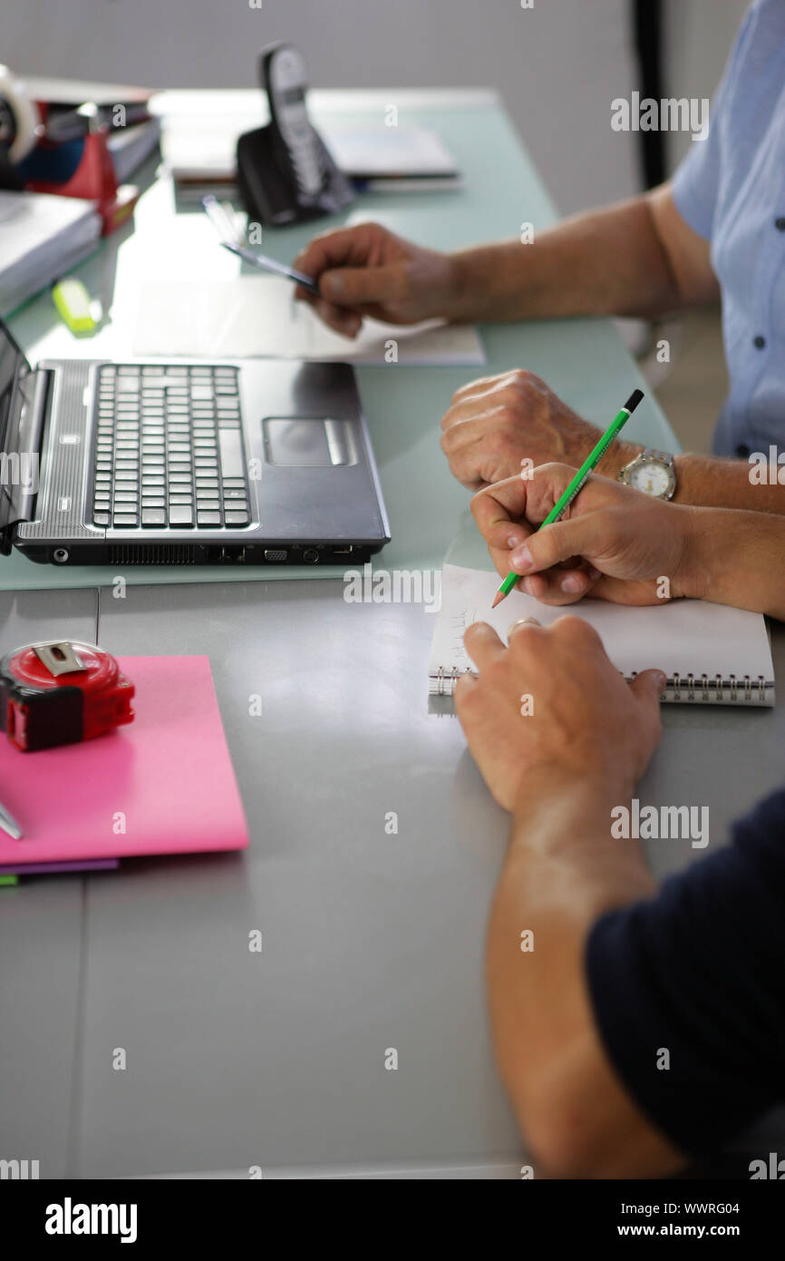 Two workers sat at desk taking notes Stock Photo - Alamy