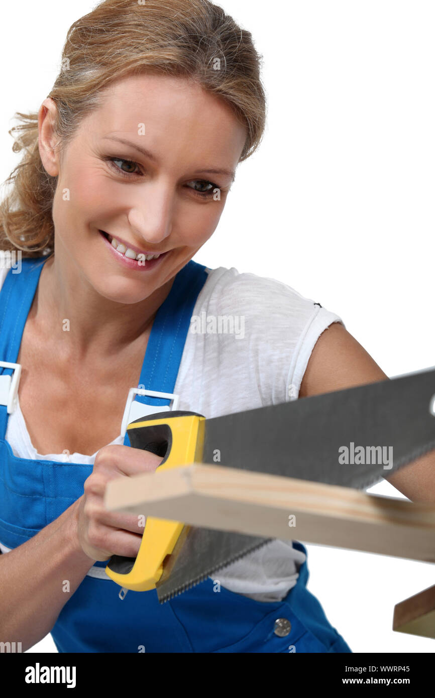 Woman wearing blue overalls sawing plank of wood Stock Photo - Alamy