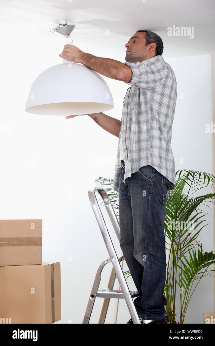 Man putting up a ceiling light Stock Photo - Alamy
