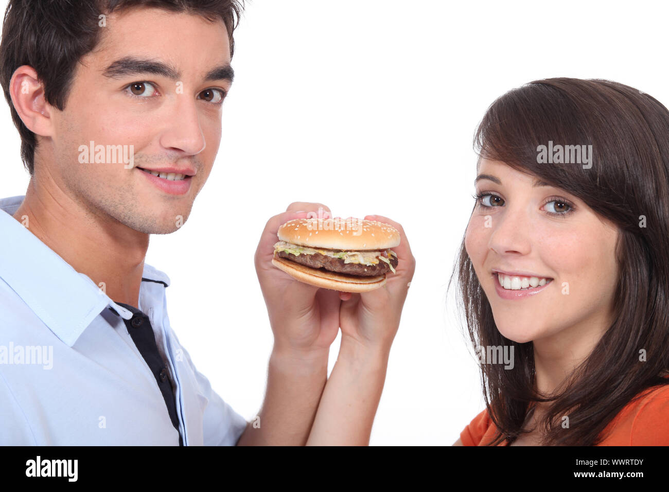 Couple stood holding a cheeseburger Stock Photo - Alamy