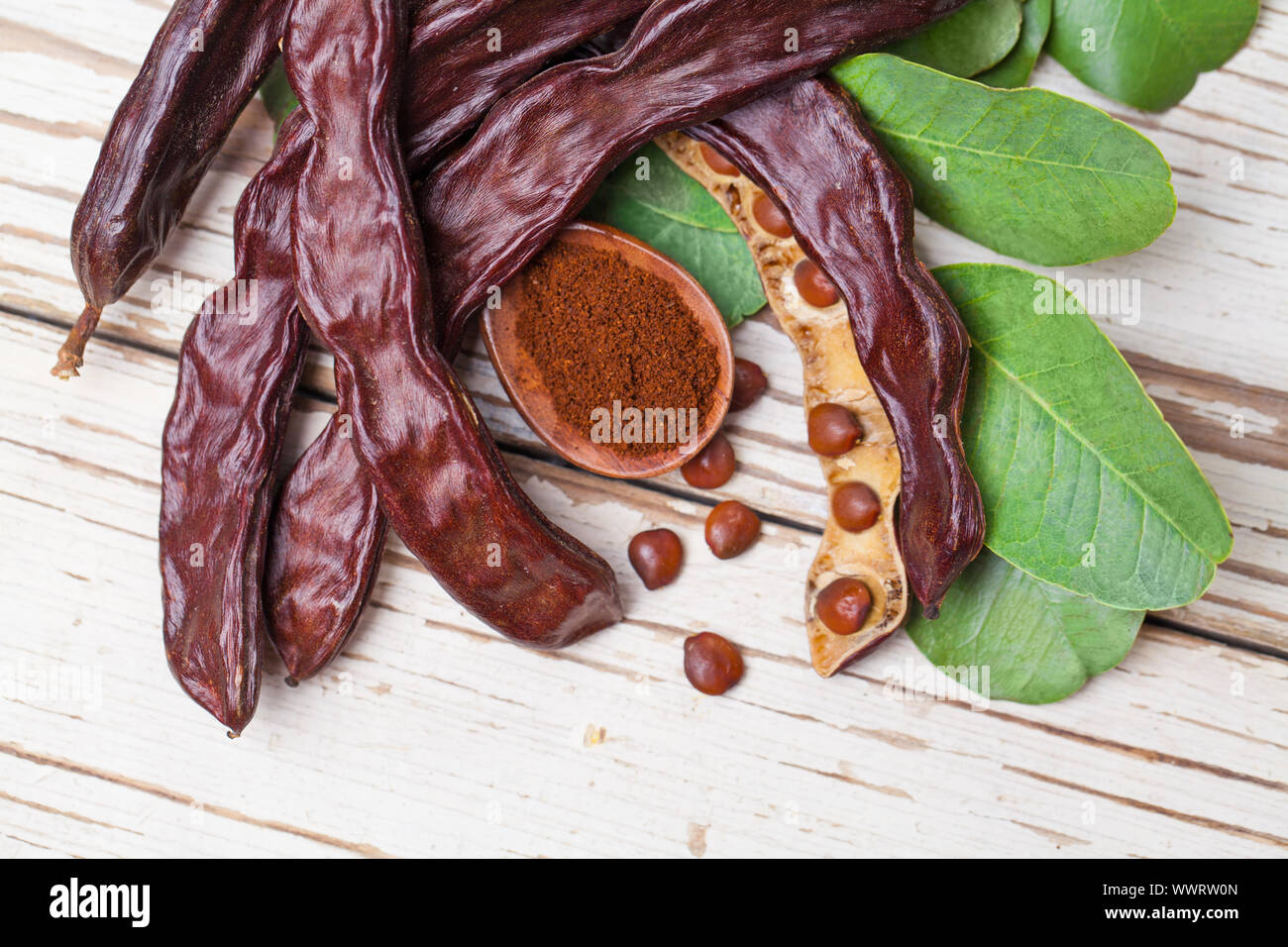 Carob with powder. Organic carob pods with seeds and leaves on white ...