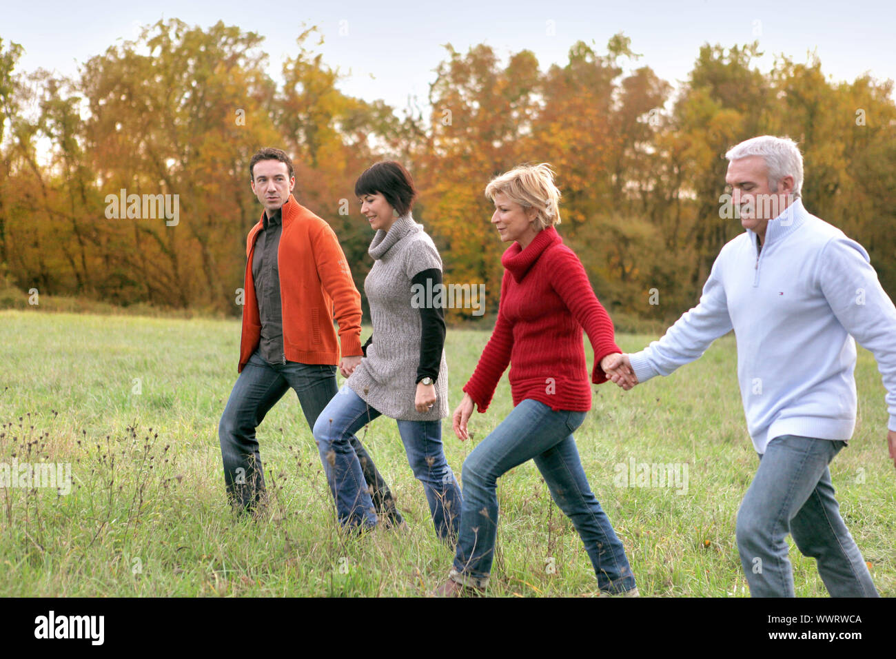 Two couples strolling across a field Stock Photo - Alamy