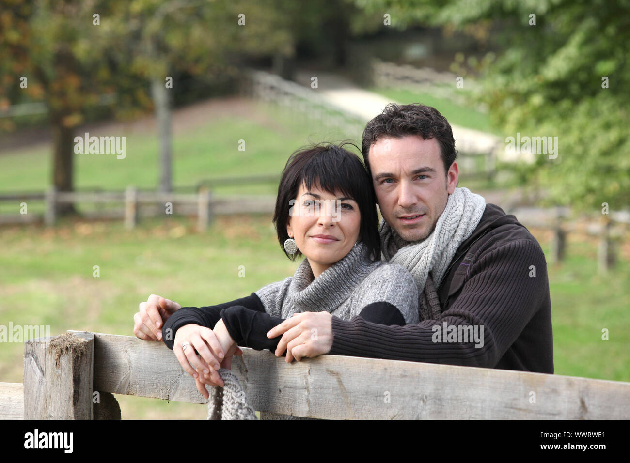 Couple stood by wooden fence Stock Photo - Alamy