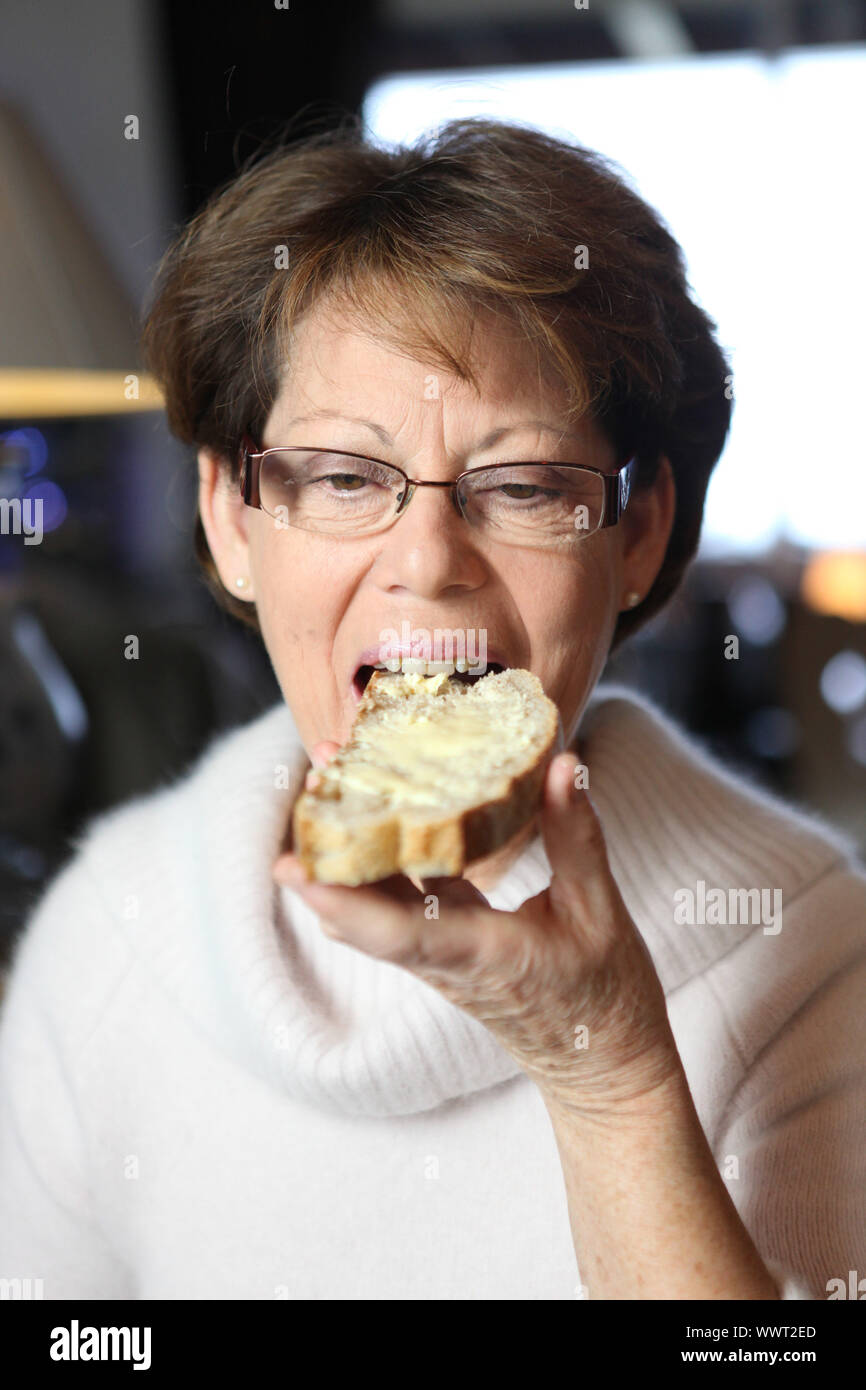 Woman eating a slice of buttered bread Stock Photo - Alamy