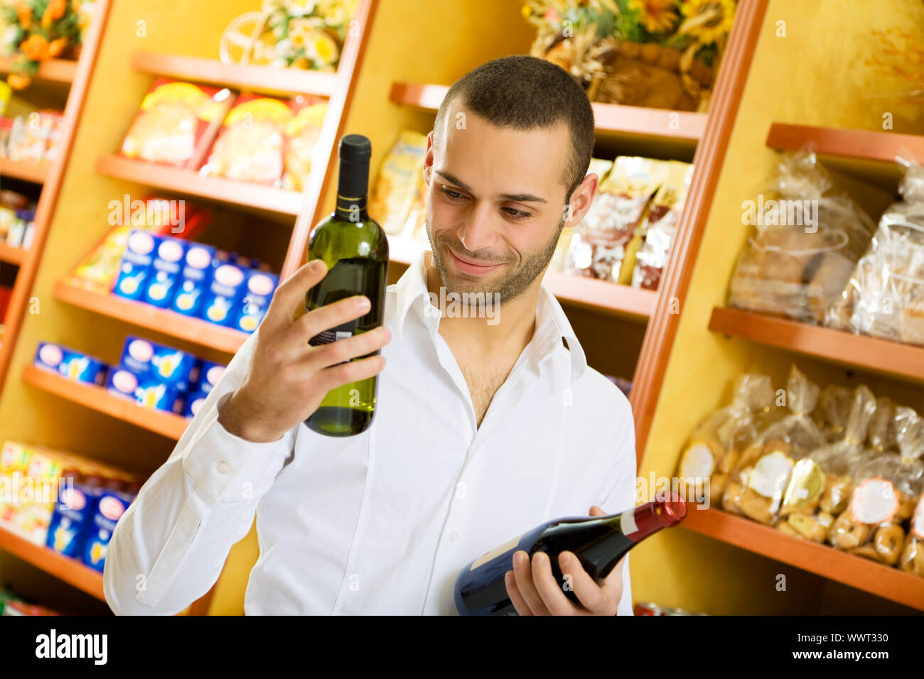 man in a supermarket comparing two wines Stock Photo - Alamy