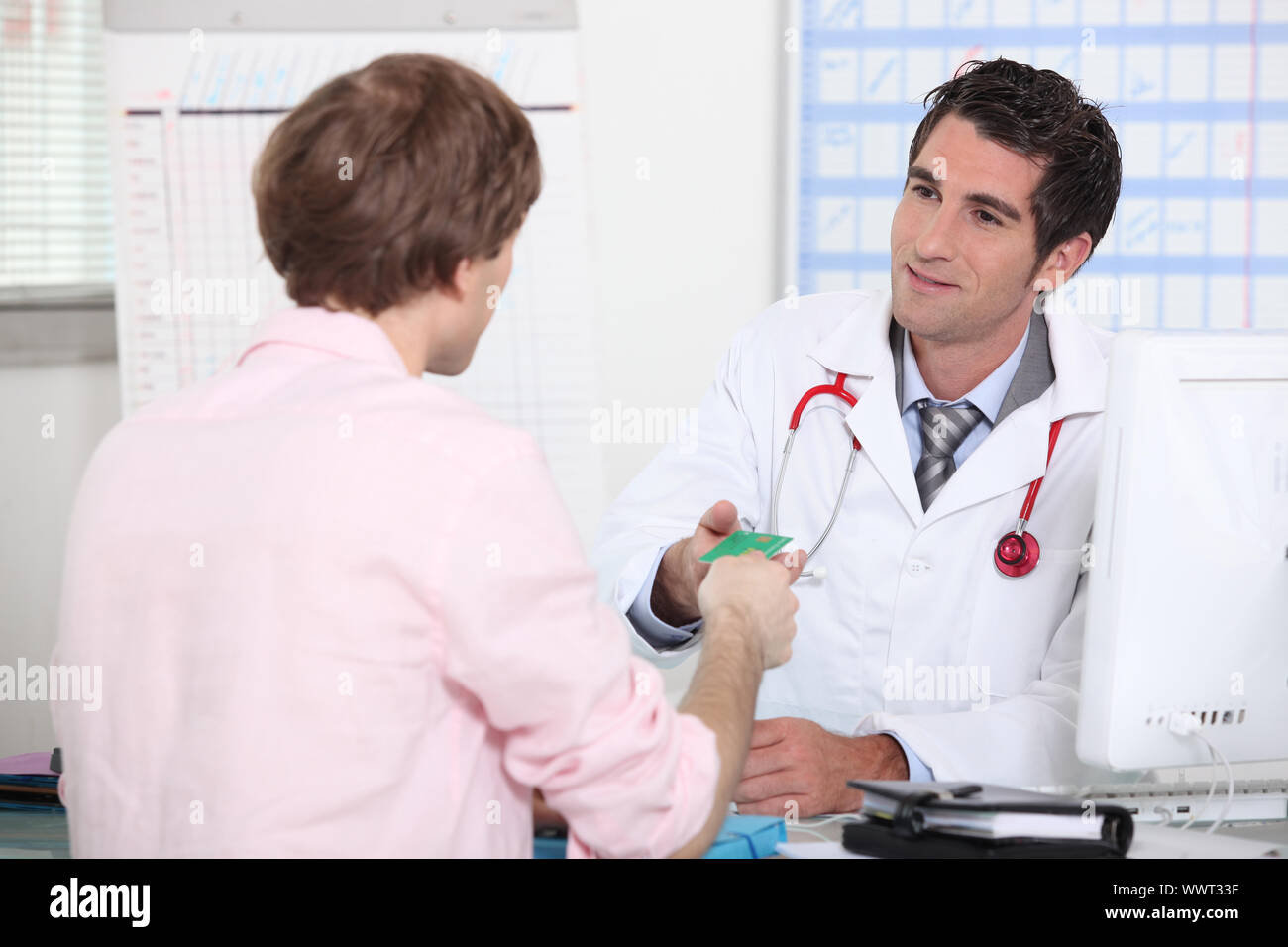 Patient handing card to doctor Stock Photo - Alamy