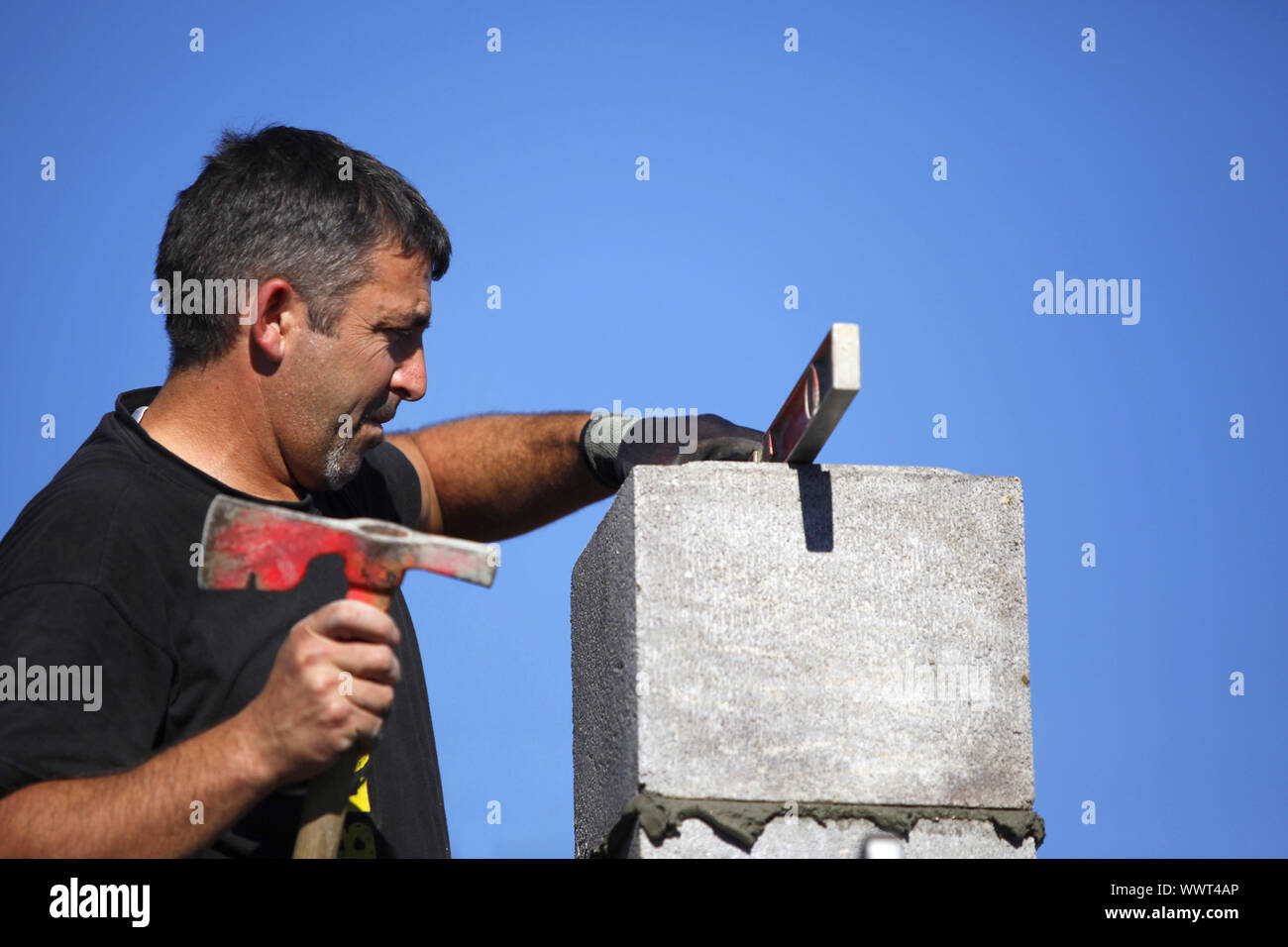 Mason making adjustment to wall Stock Photo - Alamy