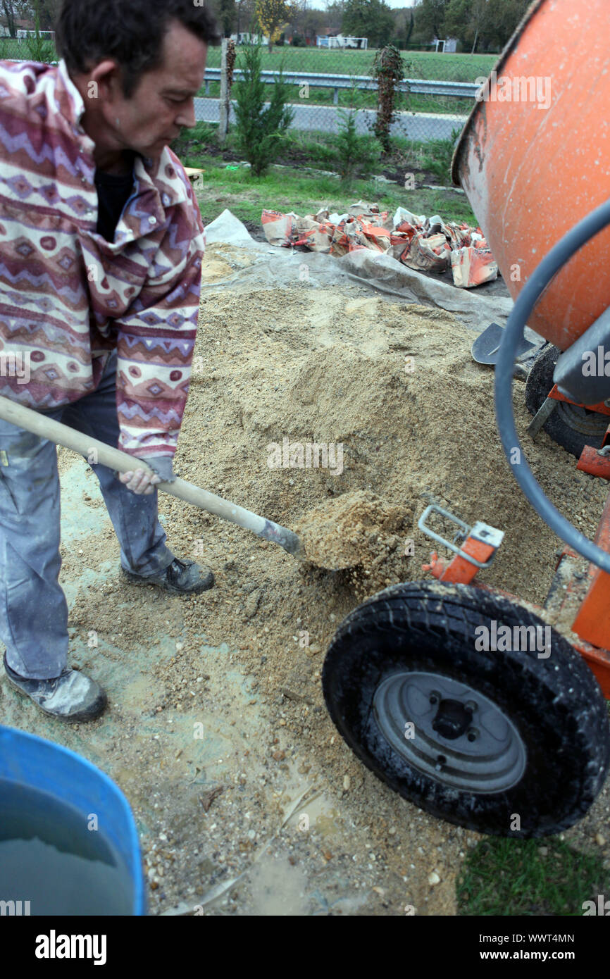 Man shovelling gravel into a mixer Stock Photo - Alamy