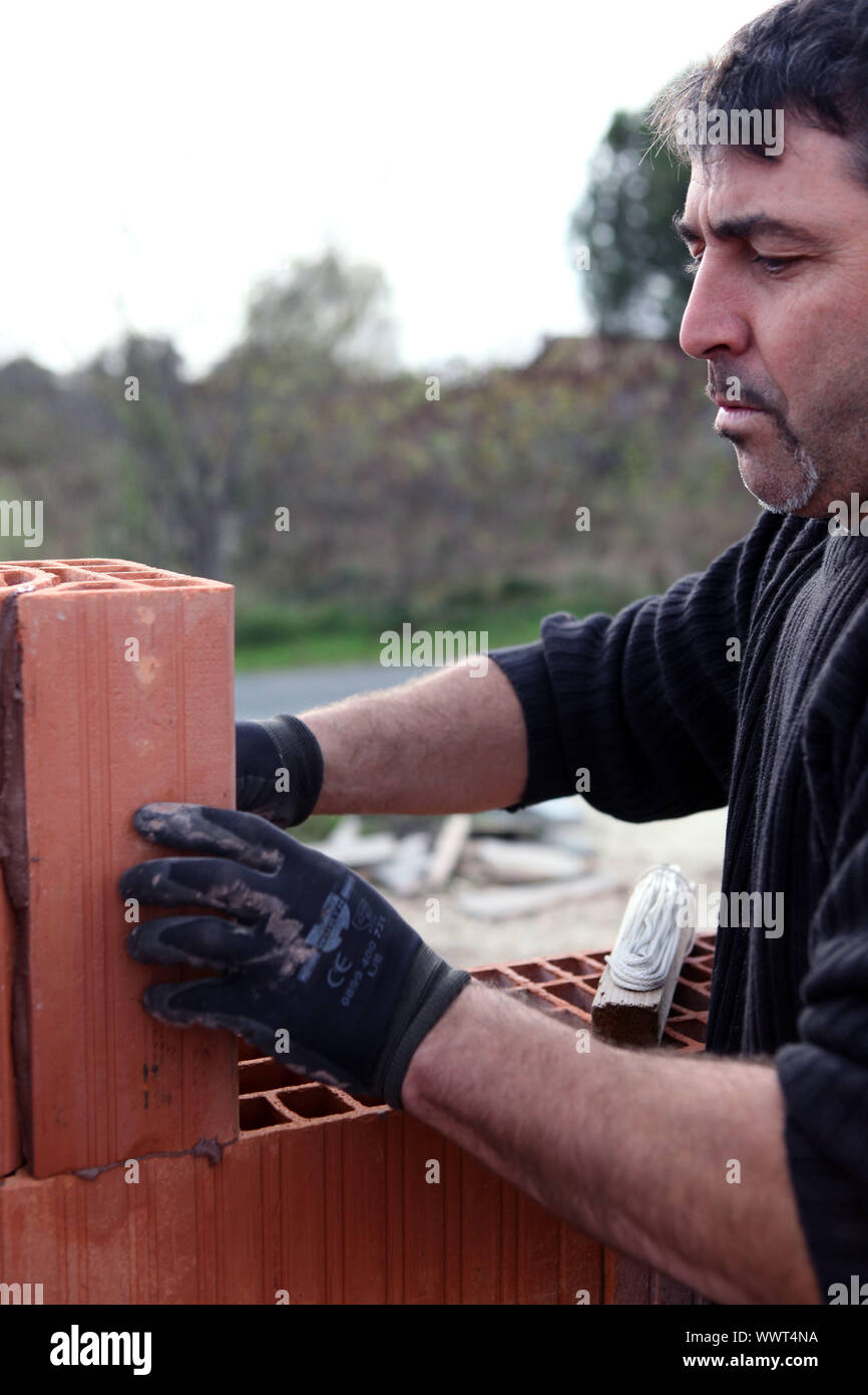 Mason working on unfinished brick wall Stock Photo - Alamy