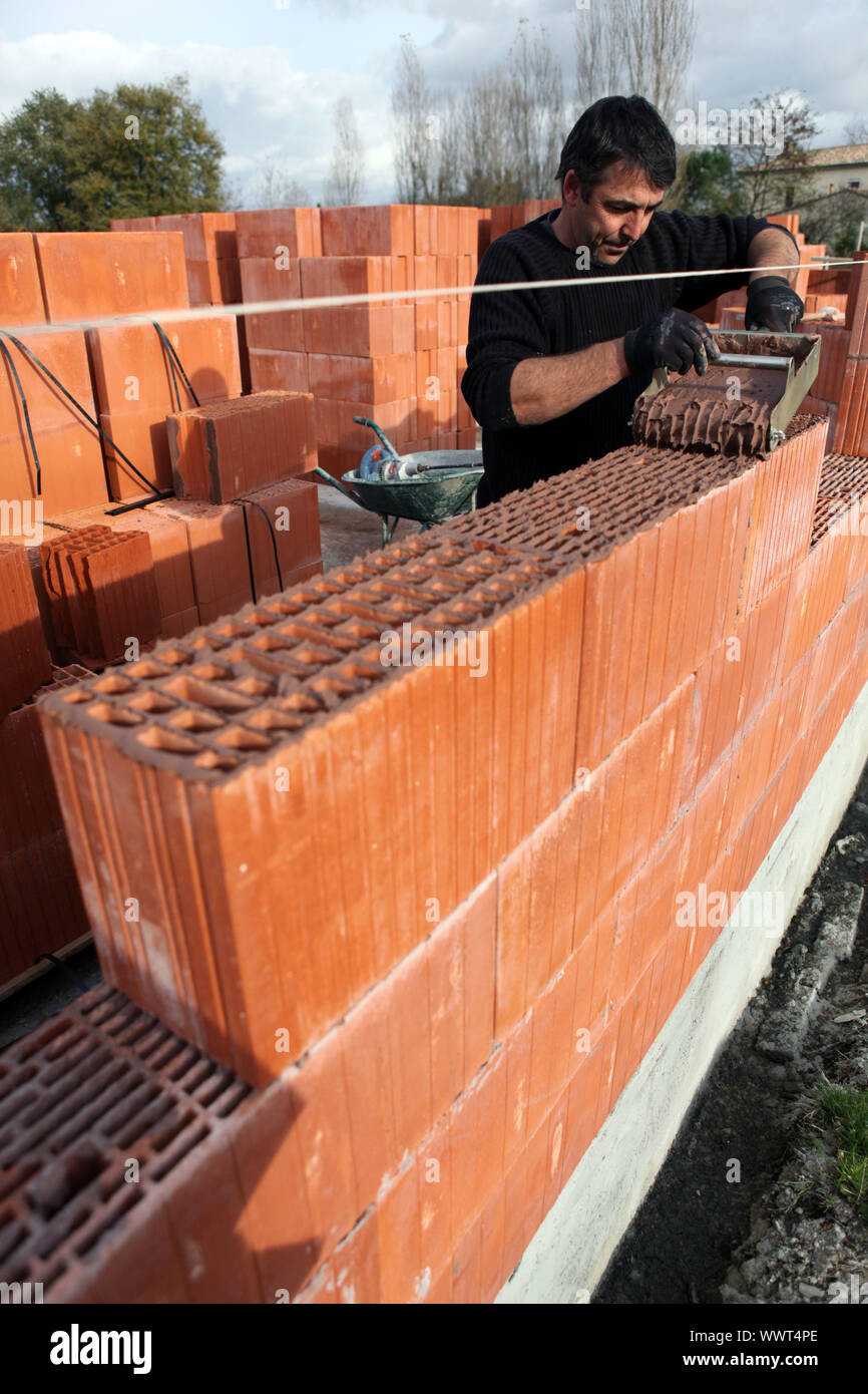 Mason building wall Stock Photo - Alamy