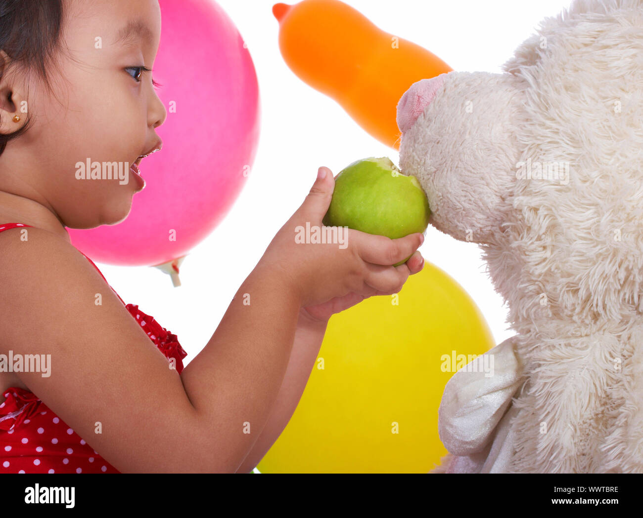 Kid Having Fun Feeding Her Teddy An Apple Stock Photo - Alamy