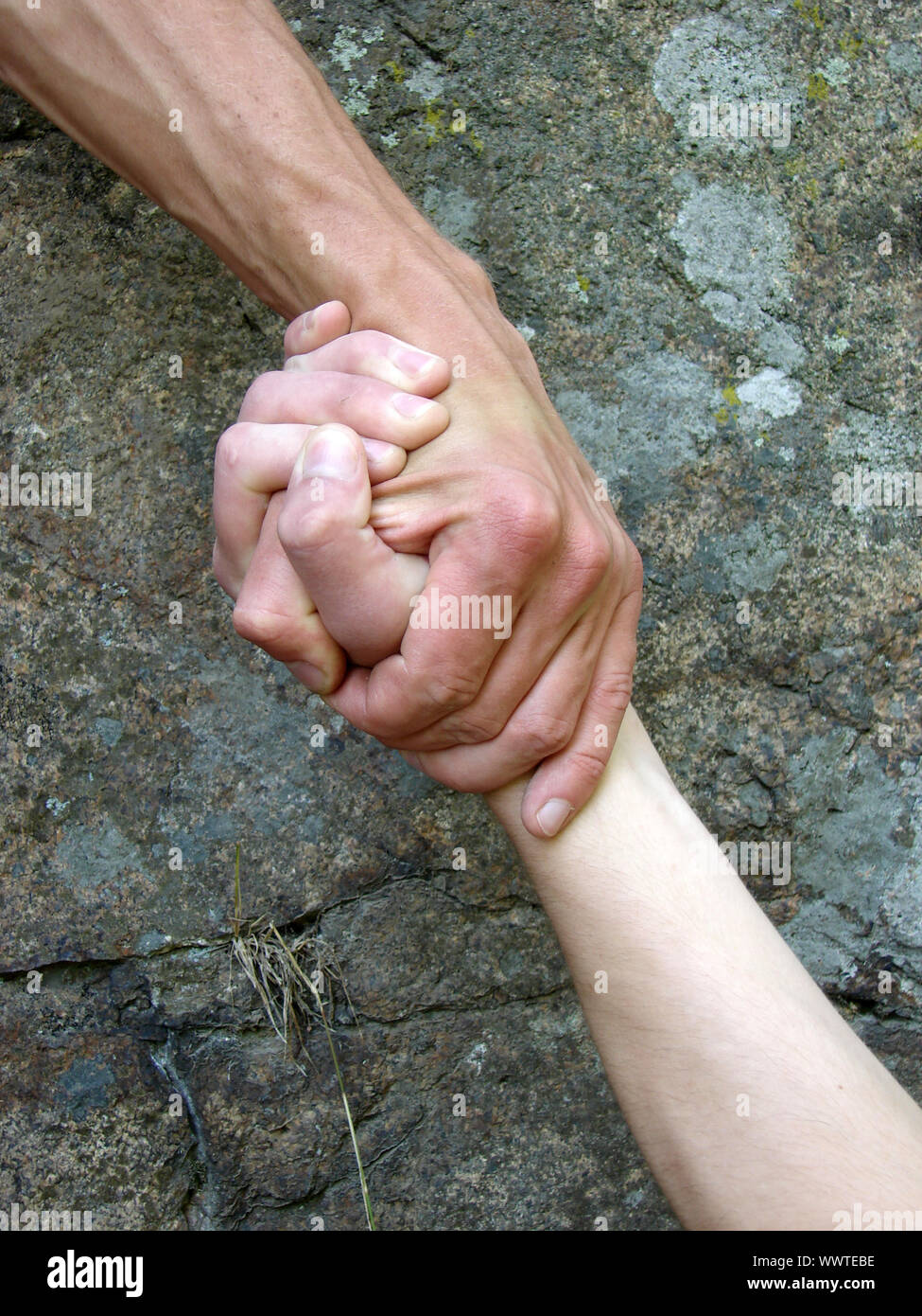 Hand in a hand on a background a rock Stock Photo - Alamy