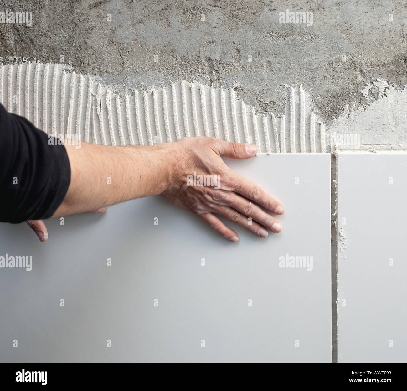 construction mason man hands on tiles work with notched trowel cement ...