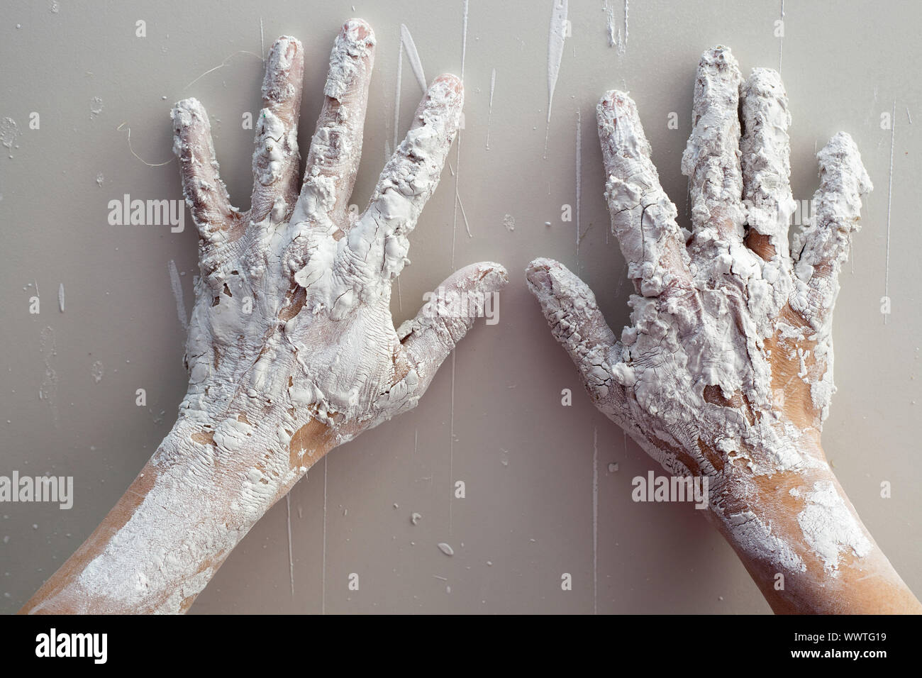 Artist plastering man hands with white dried cracked plaster texture in ...