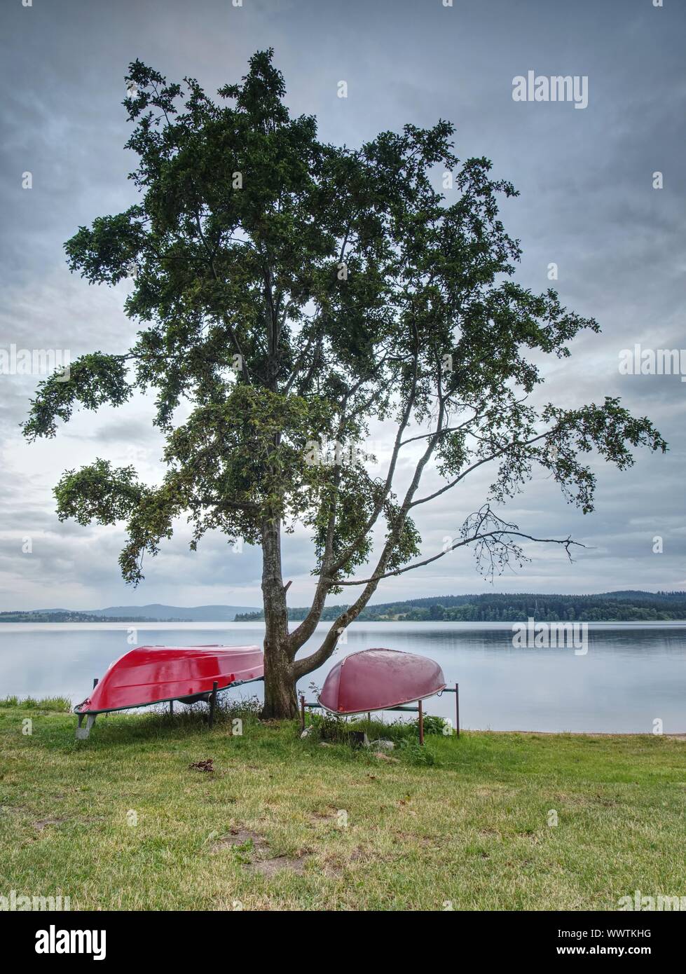Simple rowing boat stacked at lake upside down. Empty beach at popular ...