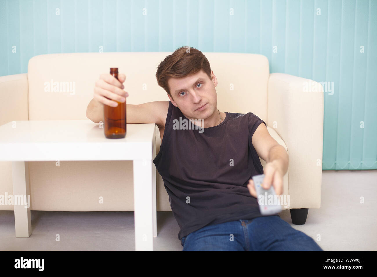 A drunk guy with a bottle of beer, the TV changes channels, sitting on ...