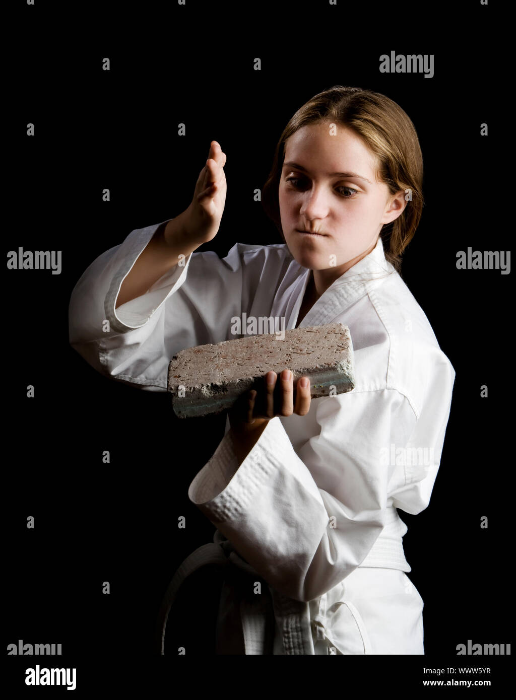 Young girl karate chopping a brick on black background Stock Photo - Alamy