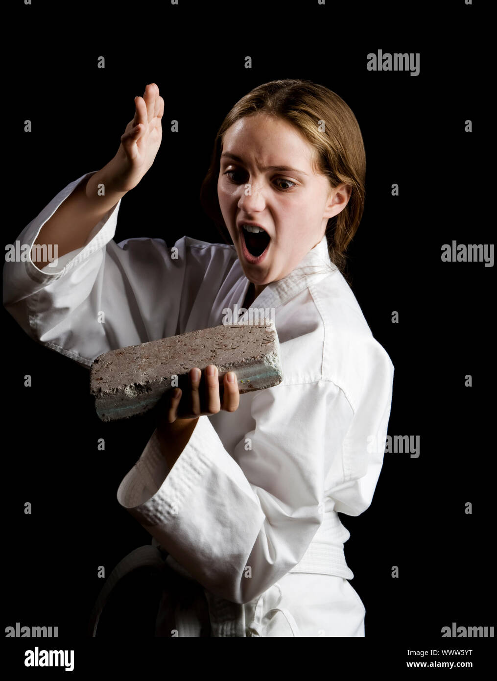 Young girl karate chopping a brick on black background Stock Photo - Alamy